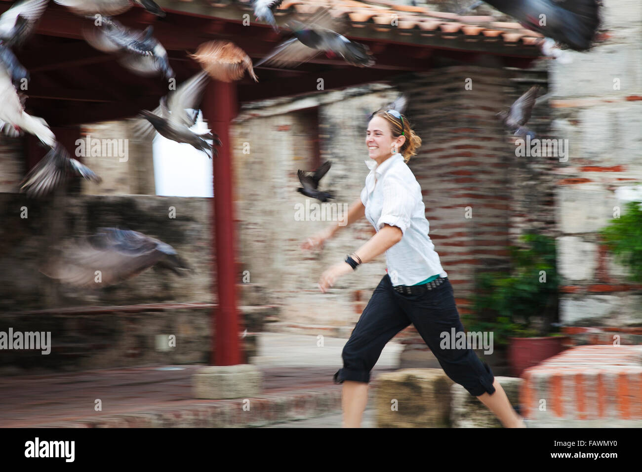 A young woman runs after a flock of birds taking flight; Cartagena ...