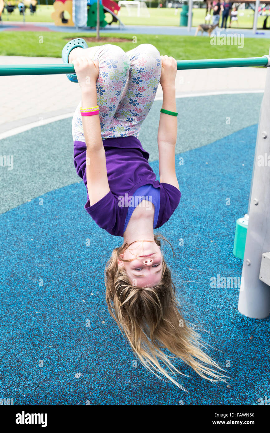Young girl hanging upside down at the playground; Salmon Arm, British Columbia, Canada Stock ...