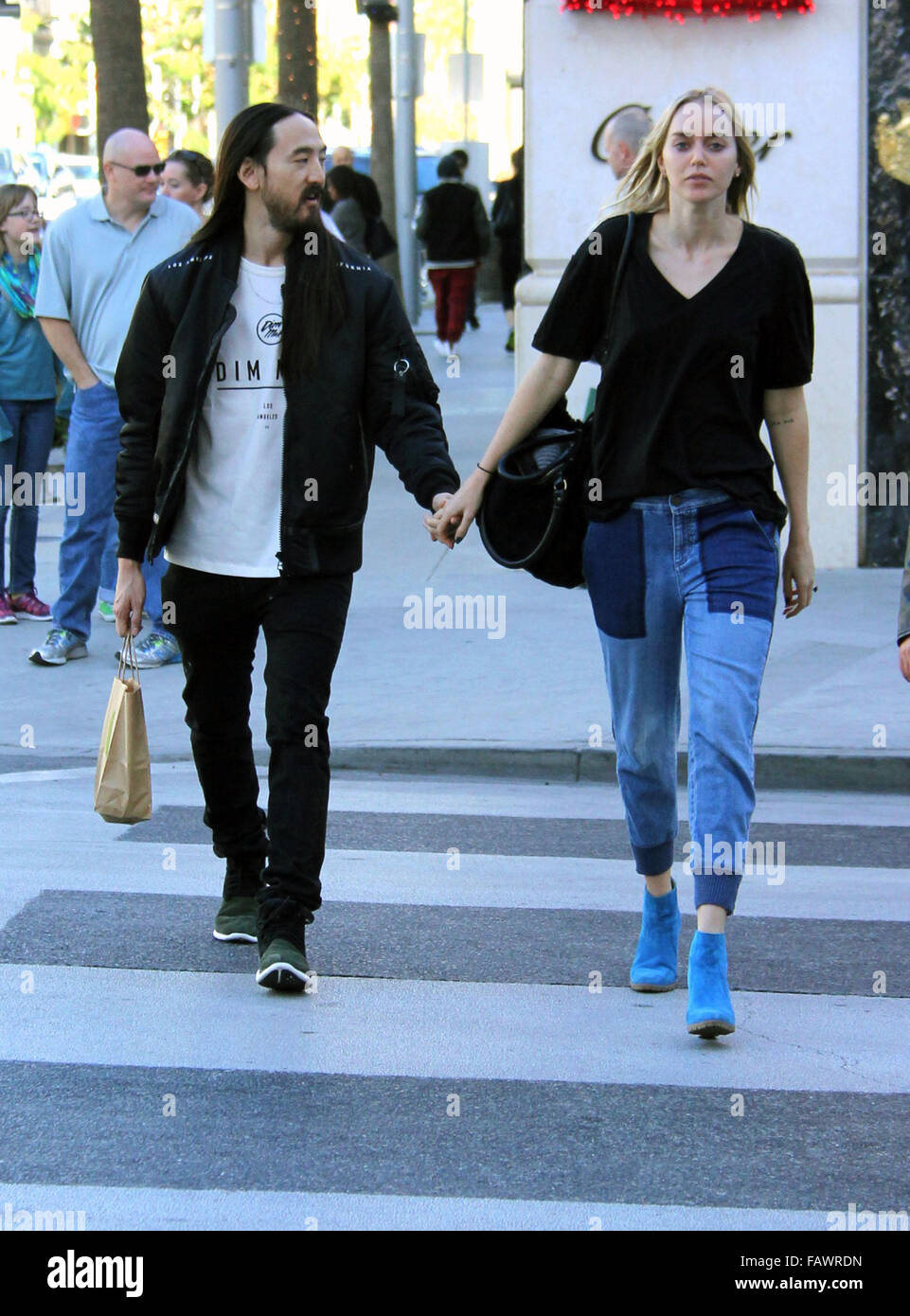 Musician Steve Aoki hold hands with his fiancee Tiernan Cowling as they ...