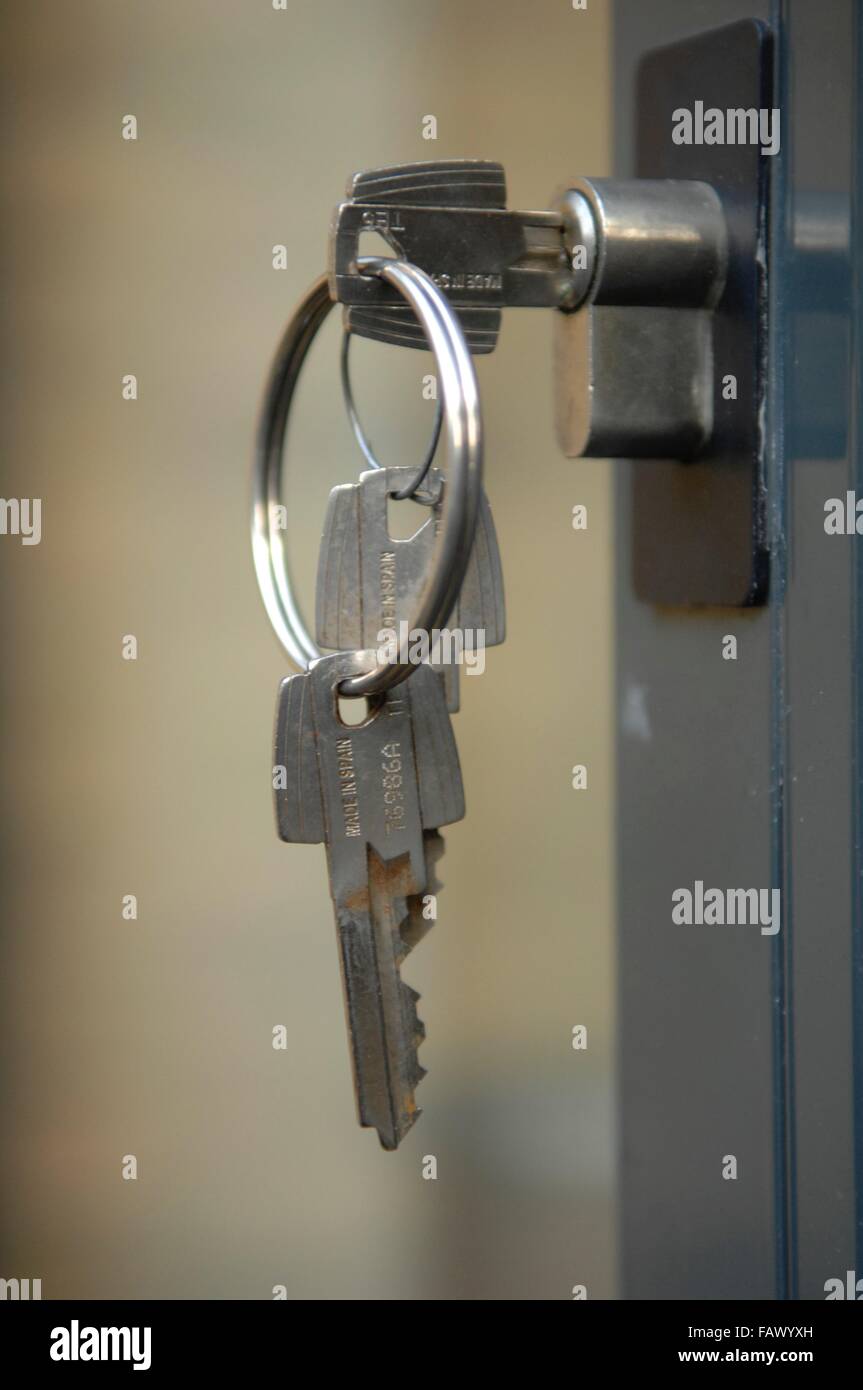 Close up of 2 keys in the lock of a door, with a fading background of ...