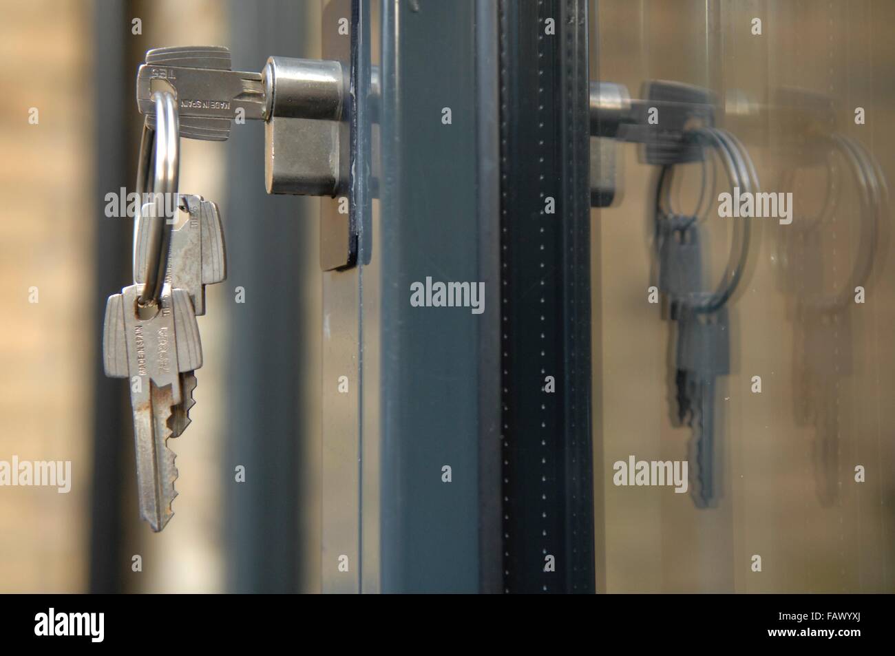 Close up of 2 keys in the lock of a door, with a fading background of ...