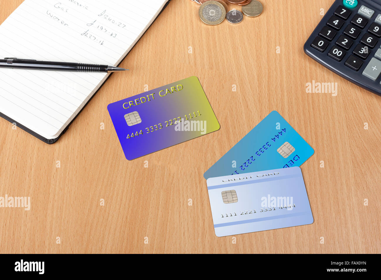 Three credit cards on a desk with a notepad, calculator and some money ...