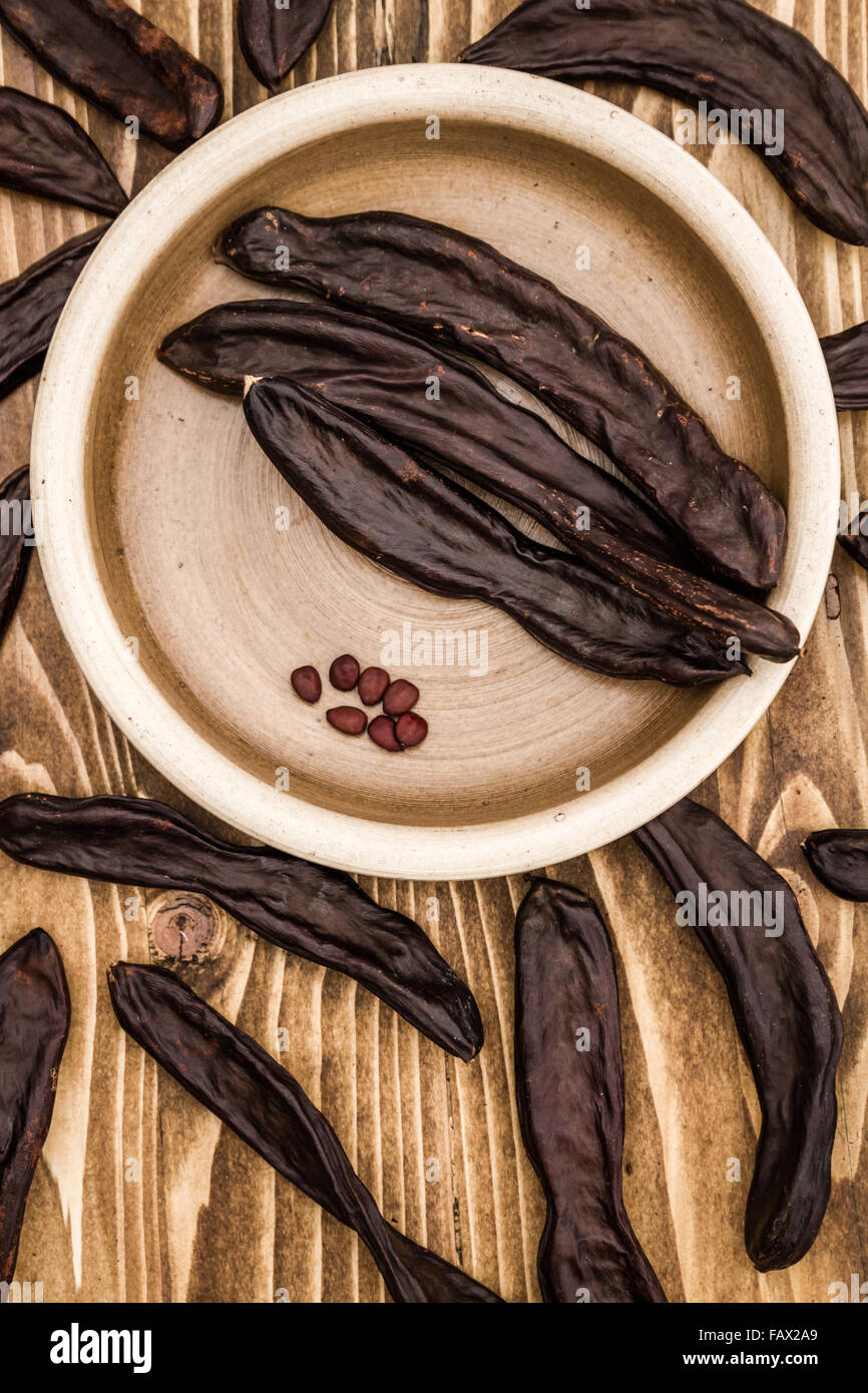 Group of dried carob pods, Ceratonia Siliqua, on wooden background ...