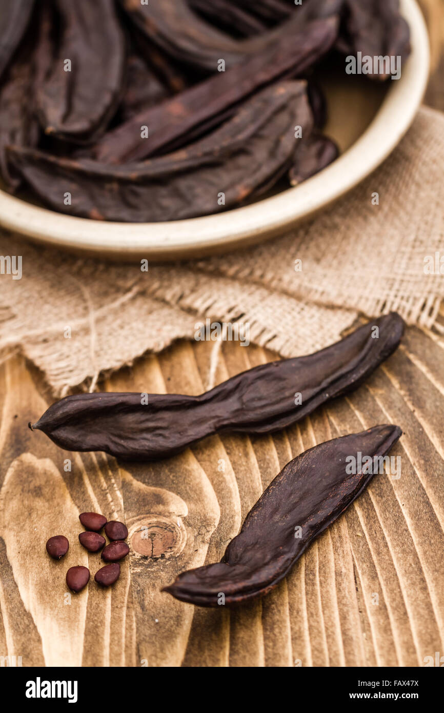 Group of dried carob pods, Ceratonia Siliqua, on wooden background ...