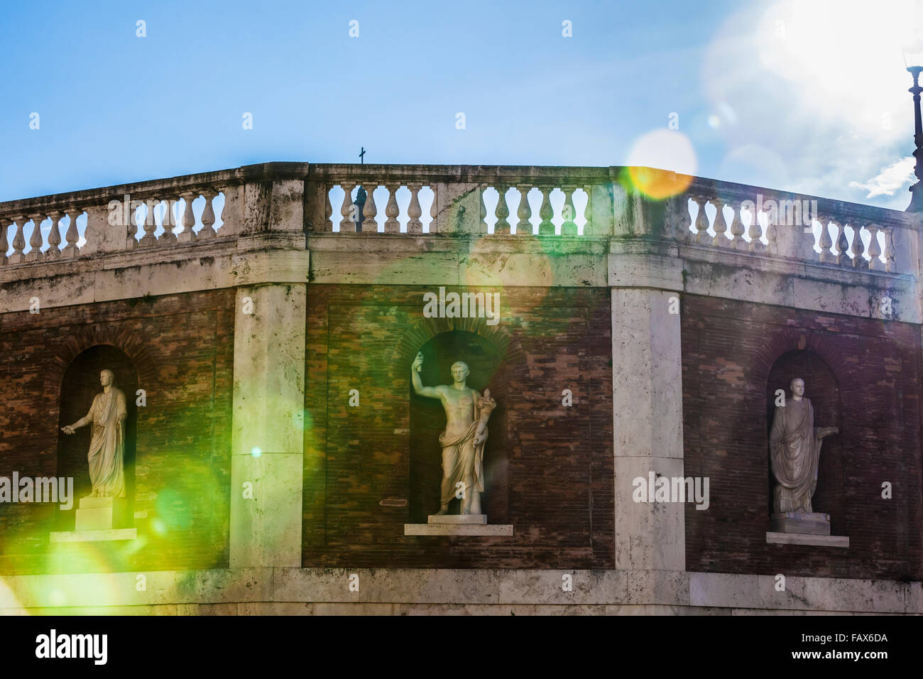 Statues in niches on a brick wall with balustrades along the top with ...