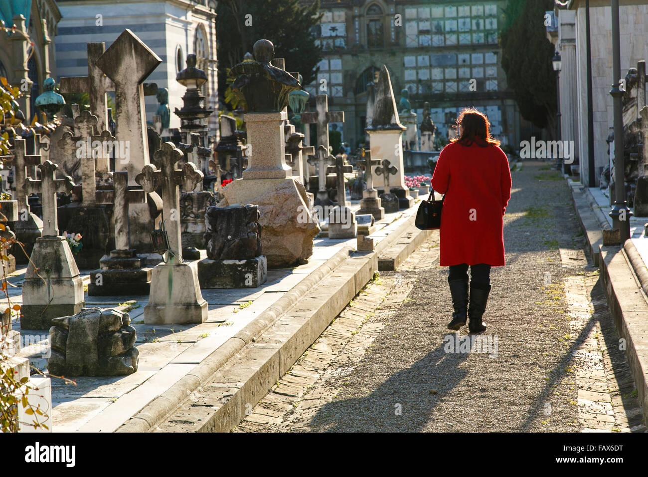 Woman in red coat soberly walking through cemetery in Florence, Italy ...