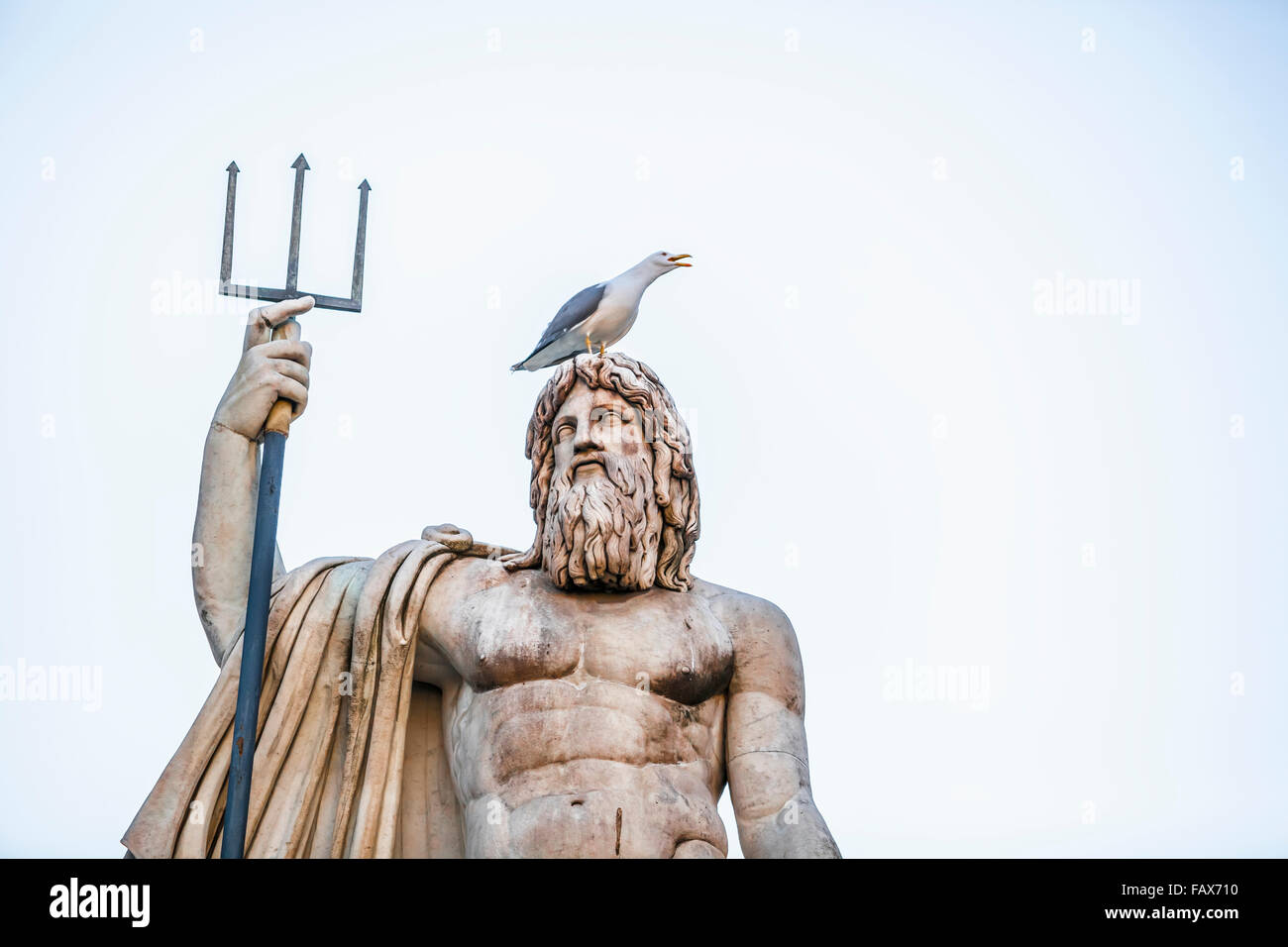 Statue of a male figure with beard and pitchfork and a bird perched on ...