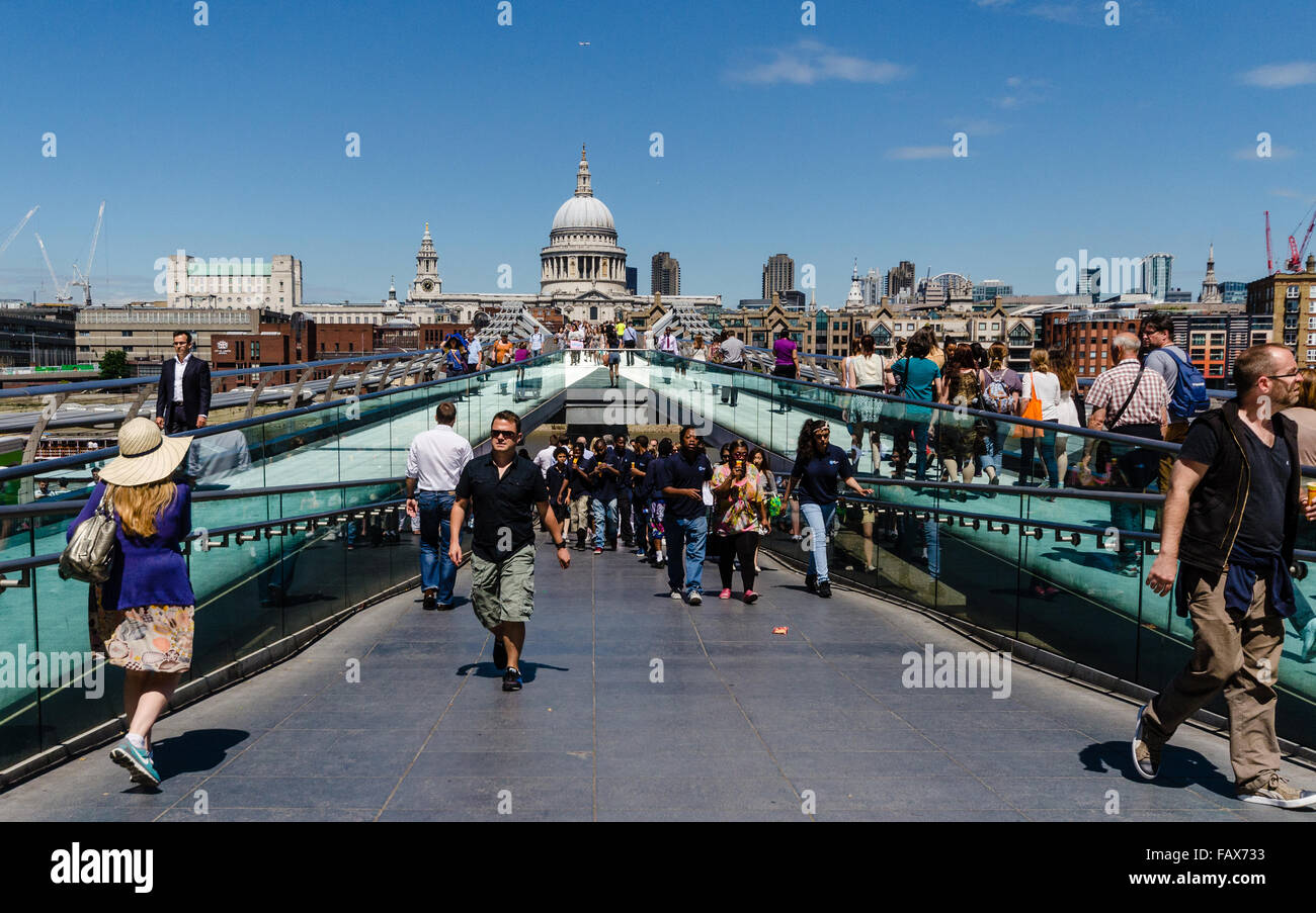 People walking over London Millennium Footbridge. Saint Pauls Cathedral ...