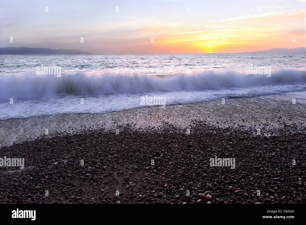 Ocean sunset is a sunset on the beach with a wave breaking on shore and ...