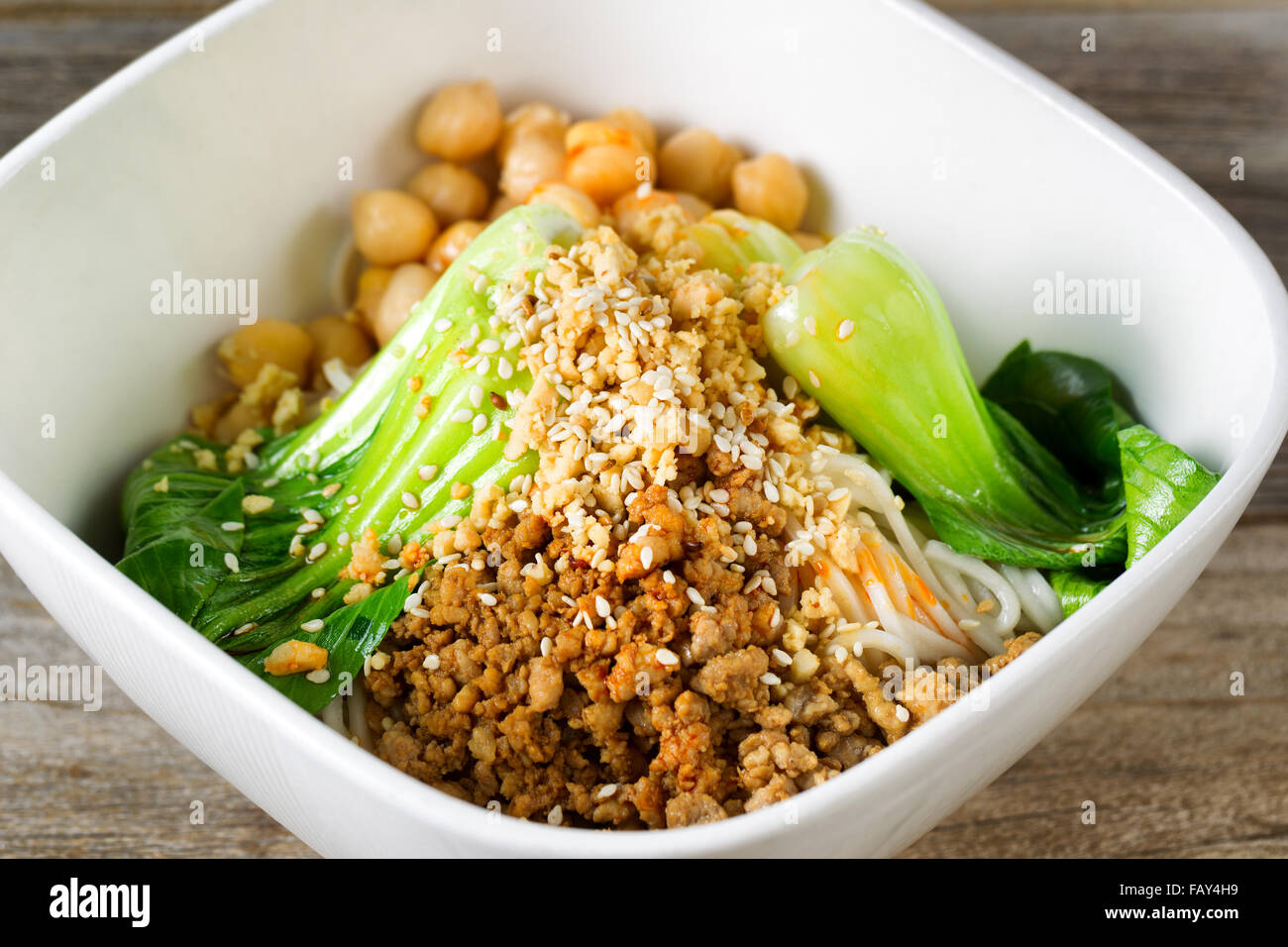 Close up front view of crispy spicy chicken with noodles and bok choy ...