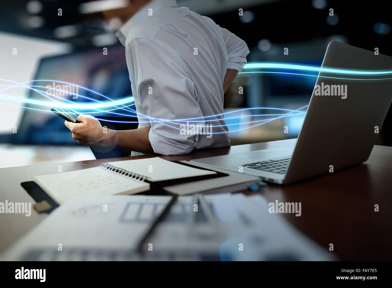 Waves of blue light and businessman using on smartphone and laptop ...