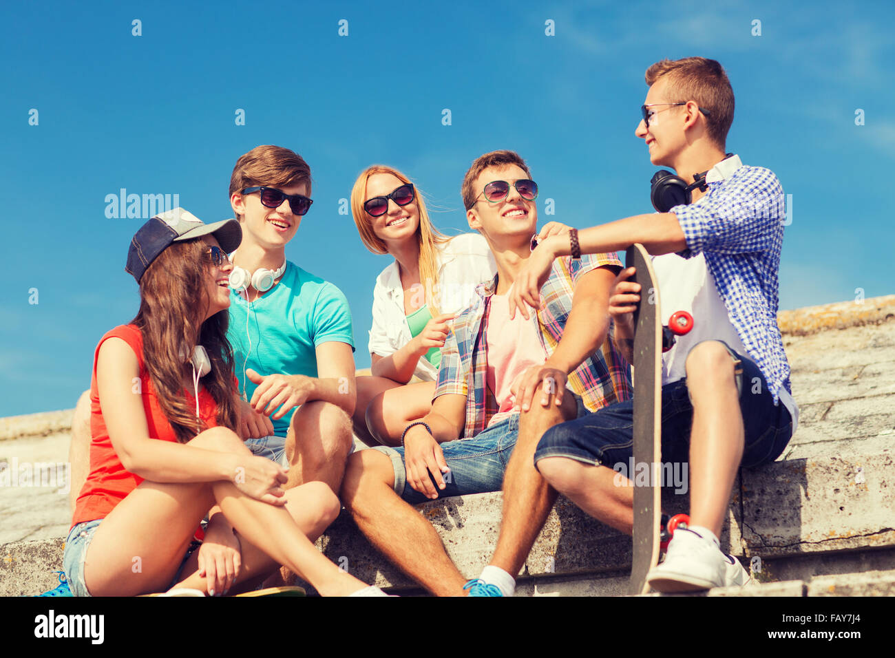 group of smiling friends sitting on city street Stock Photo - Alamy
