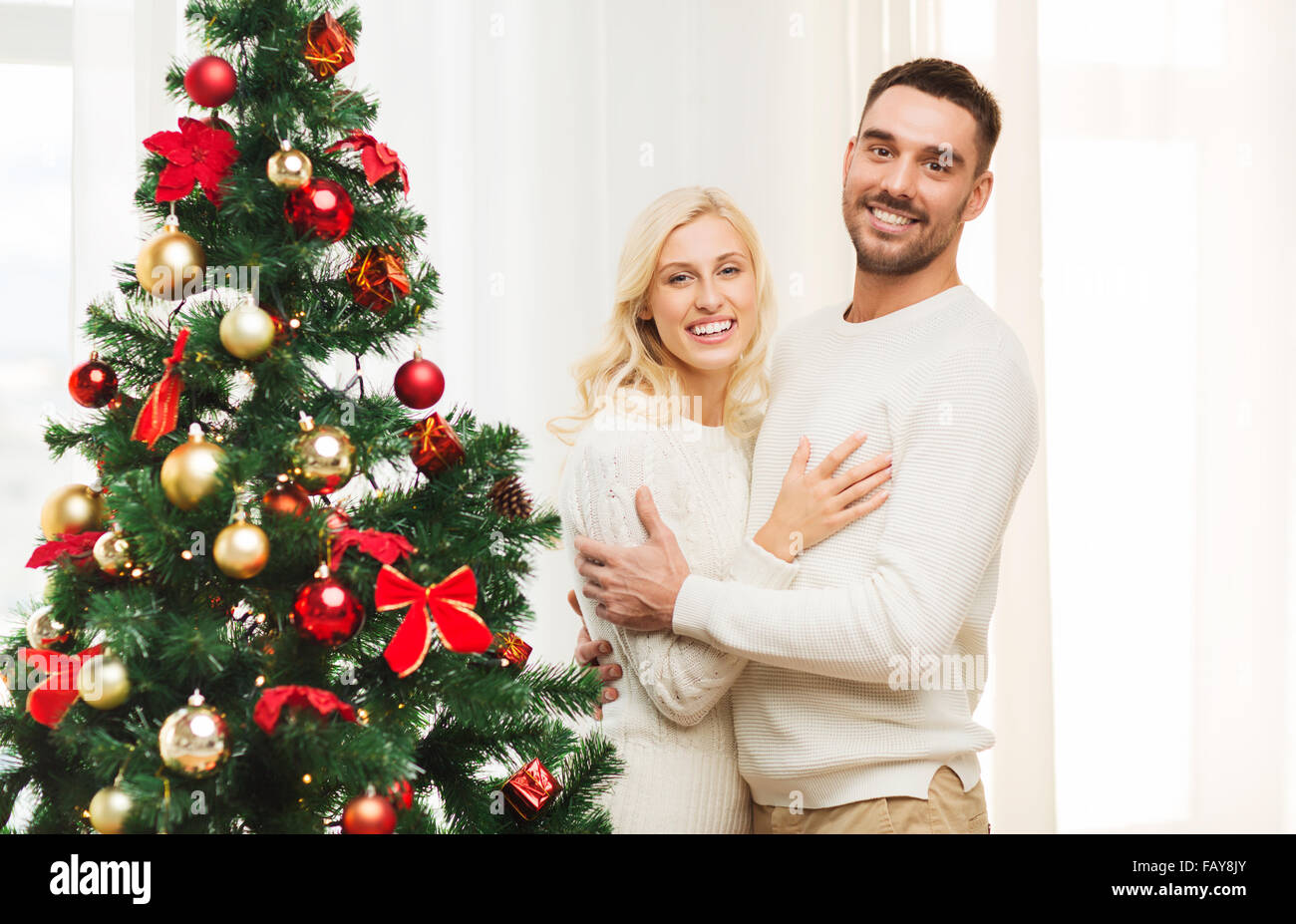 happy couple hugging near christmas tree at home Stock Photo - Alamy
