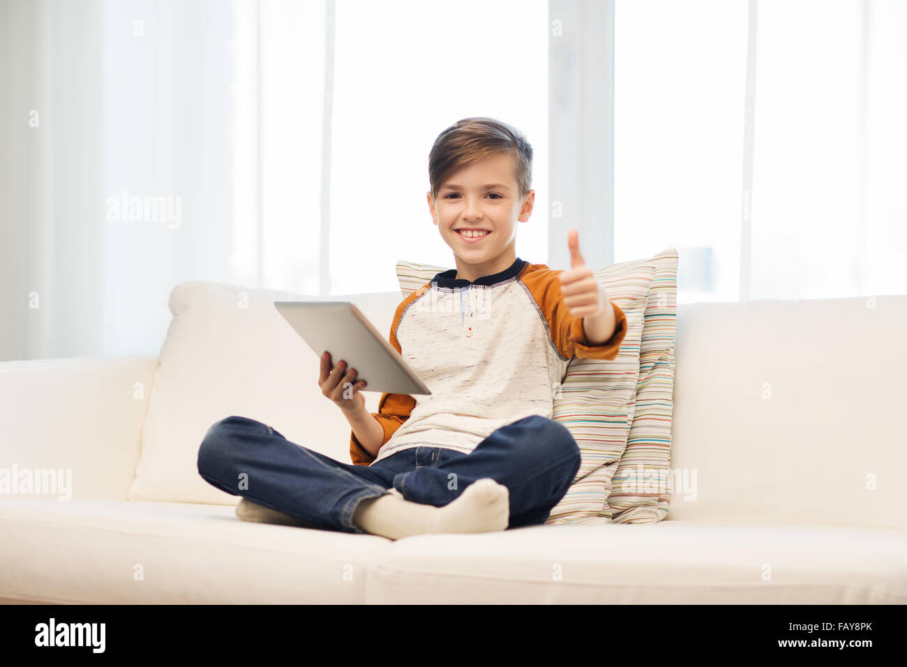 smiling boy with tablet showing thumbs up at home Stock Photo - Alamy