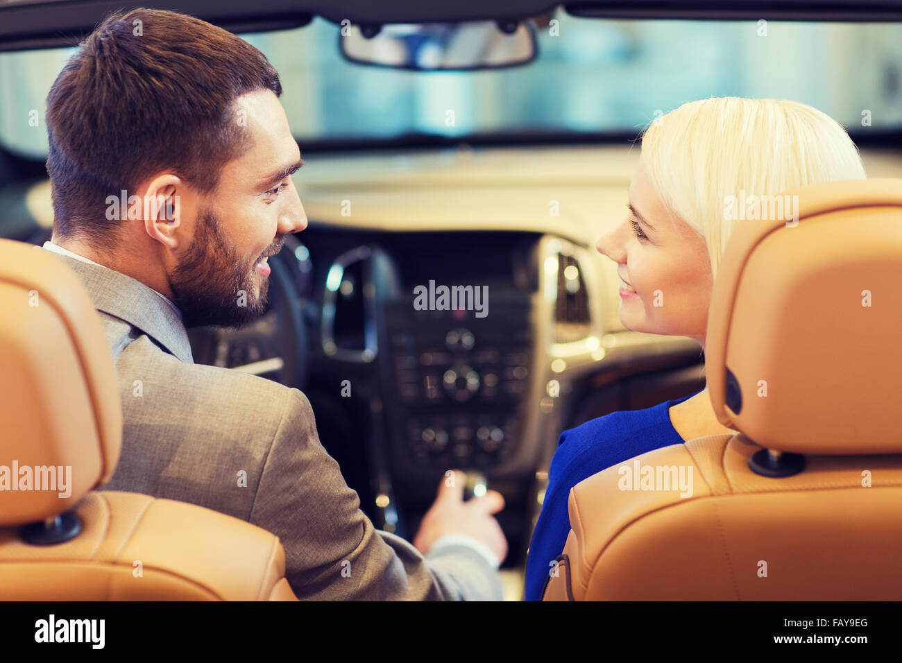 happy couple sitting in car at auto show or salon Stock Photo - Alamy