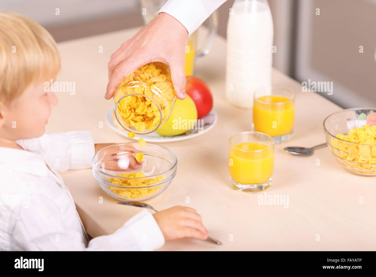 Dad offers cornflakes to his kid Stock Photo - Alamy