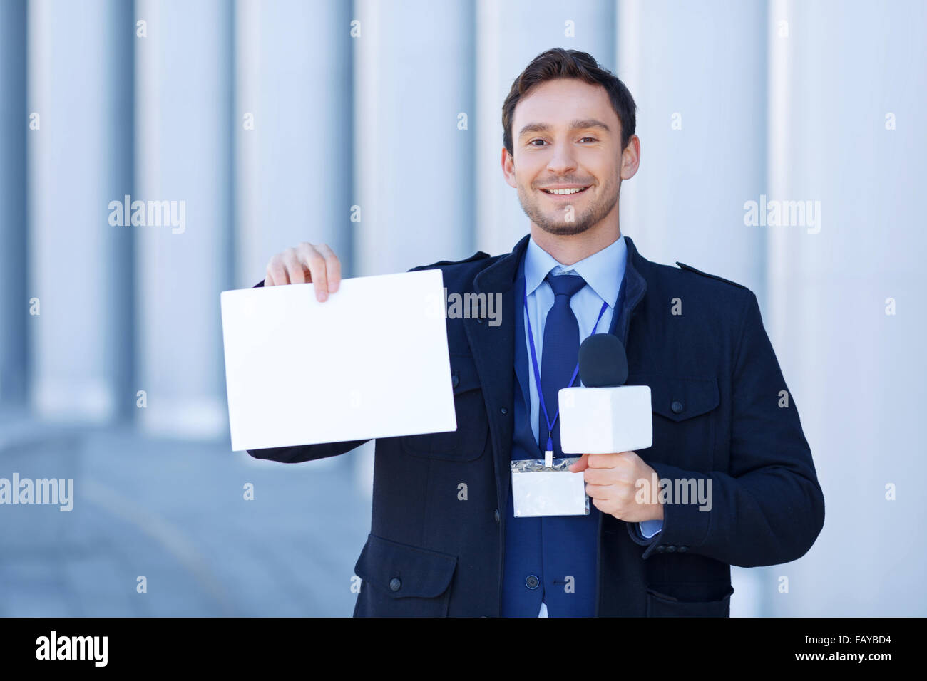 Smiling reporter with microphone holds a sheet of paper Stock Photo - Alamy