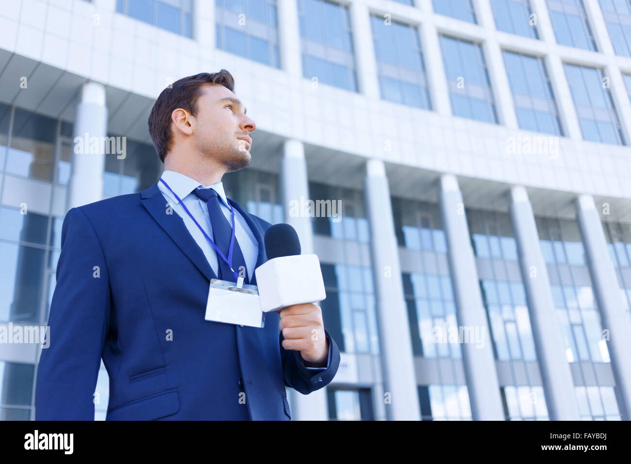 Journalist with microphone stands near the office Stock Photo - Alamy