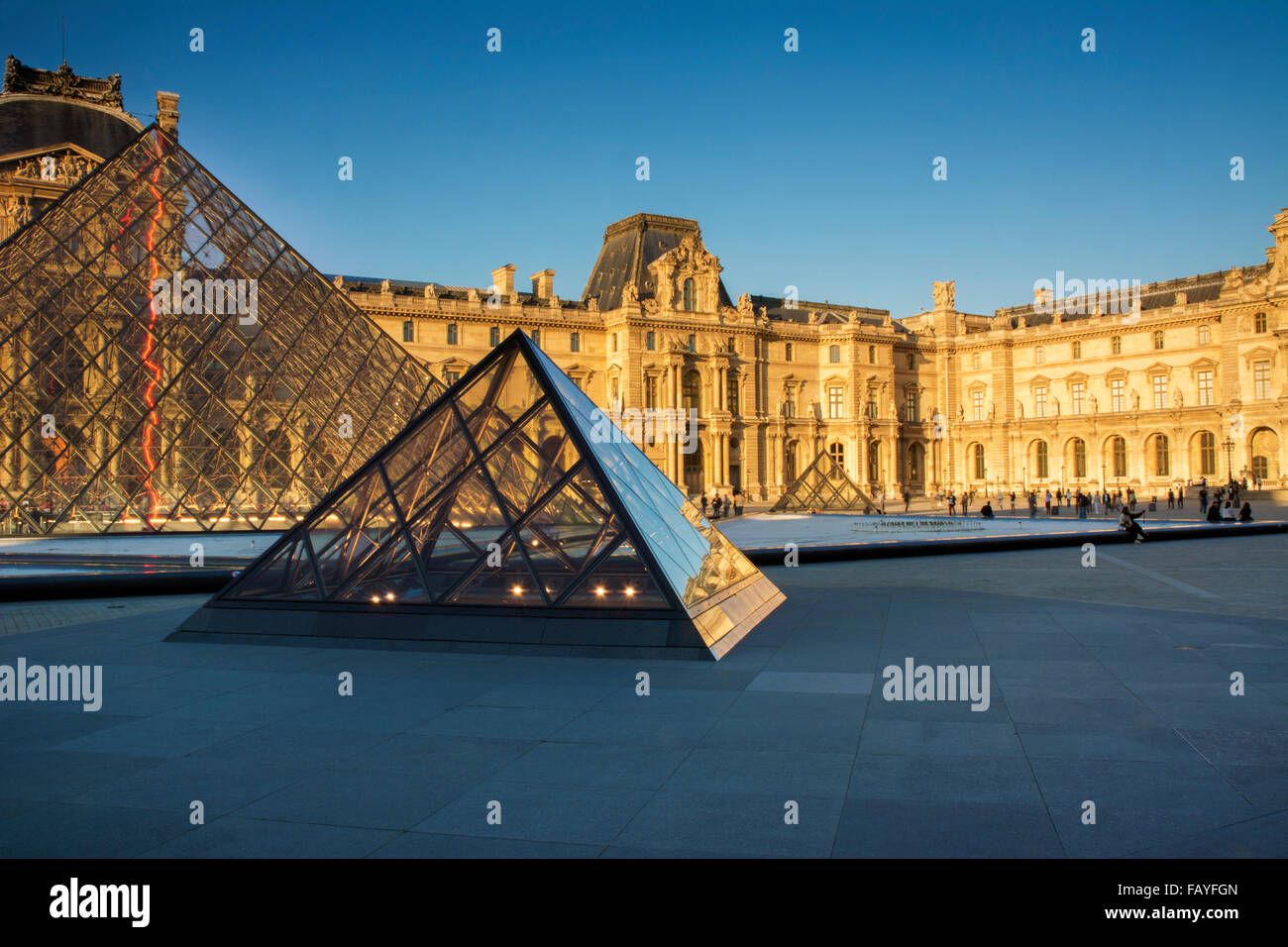 Pyramids and buildings of Le Louvre palace in golden evening light ...