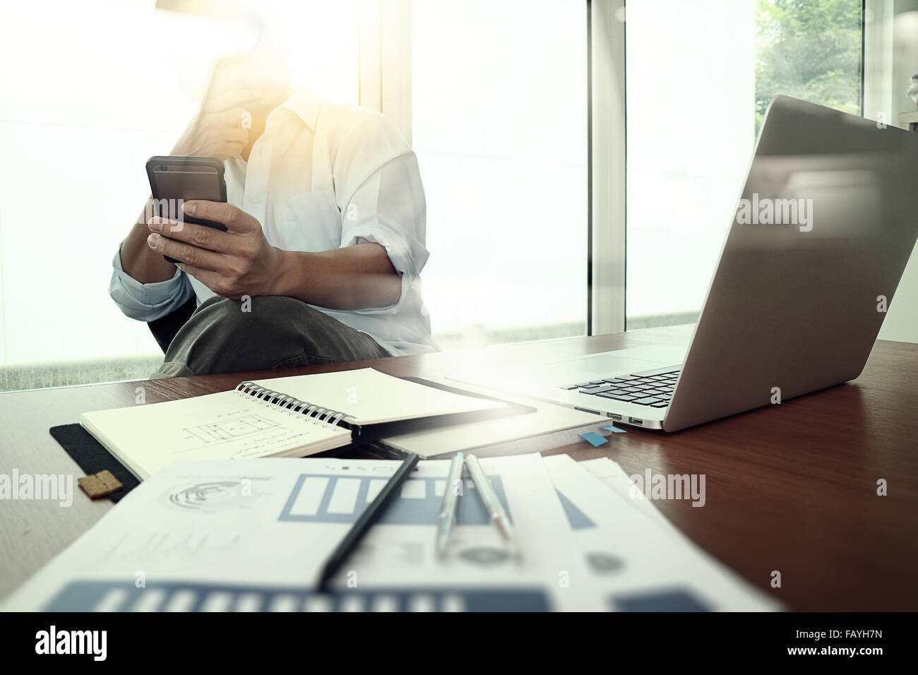 designer hand working and smart phone and laptop on wooden desk in ...