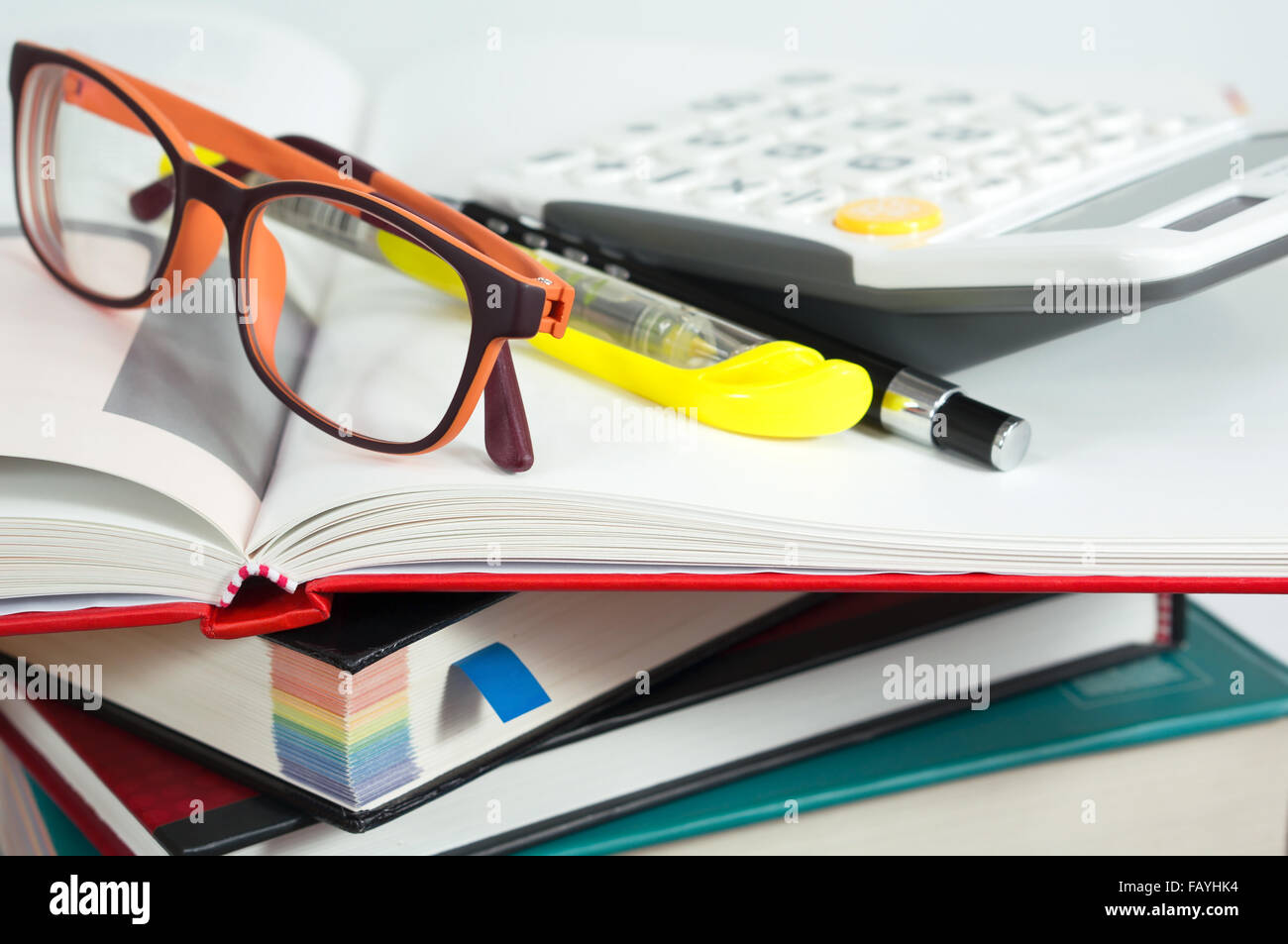 Book stack with eyeglasses and calculator Stock Photo - Alamy