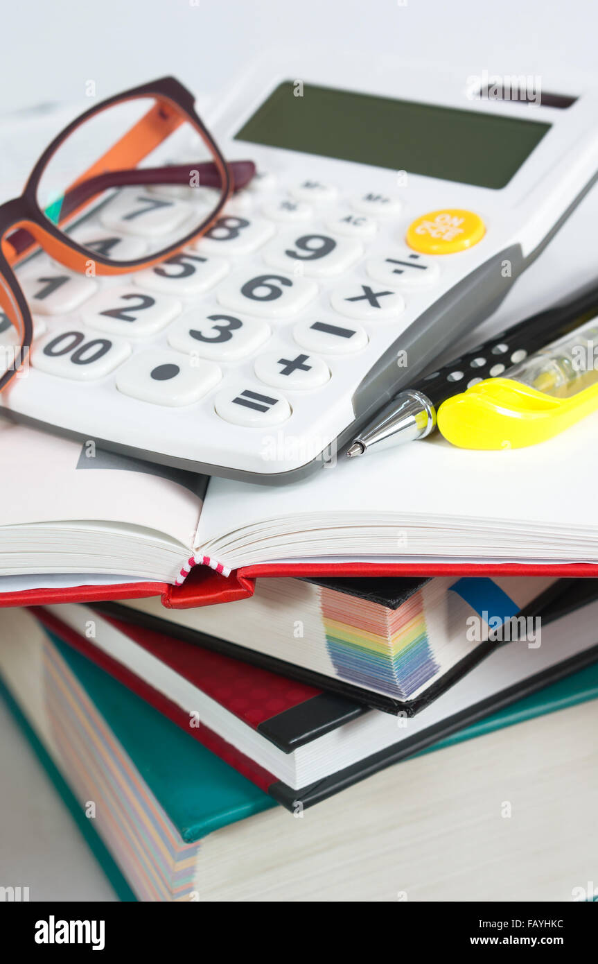 Calculator and pen on book stack with eyeglasses for financial and ...