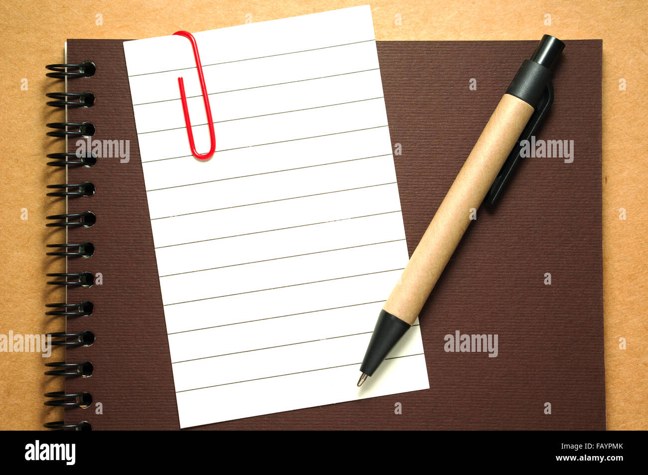Note paper clip on notebook with pen on brown cardboard background ...
