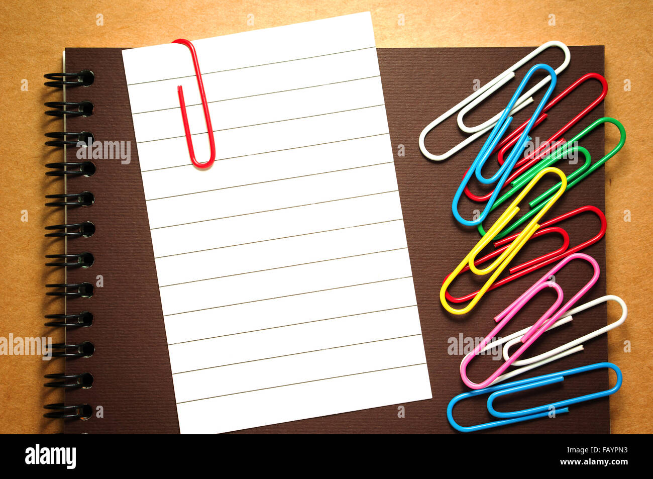 Note paper clip on brown notebook with colorful paperclips Stock Photo ...