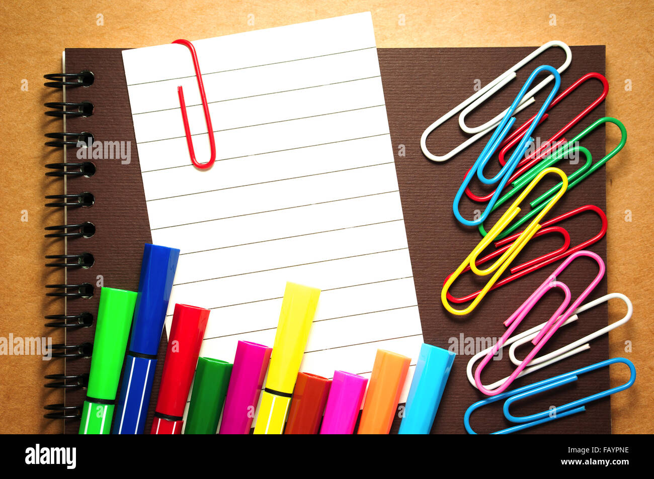 Note paper clip on notebook with colorful marker pens and paperclips on ...