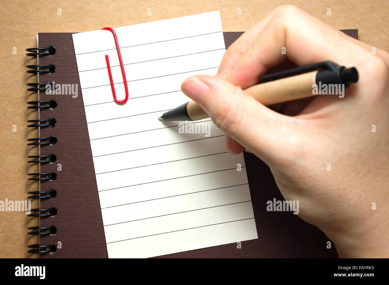 Note paper with hand holding pen on kraft cardboard background Stock ...