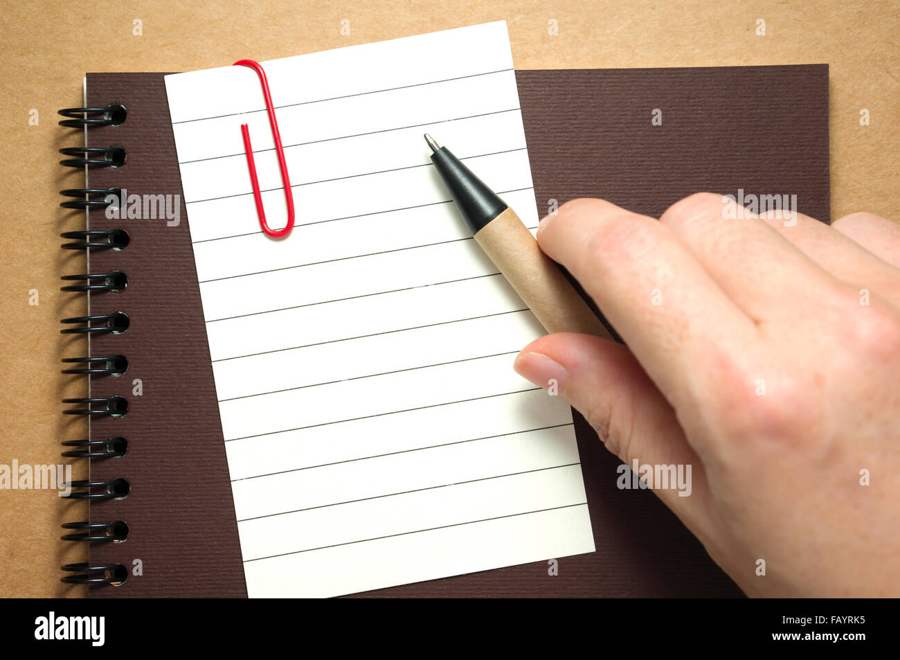 Note paper on notebook with hand and pen on kraft cardboard background ...