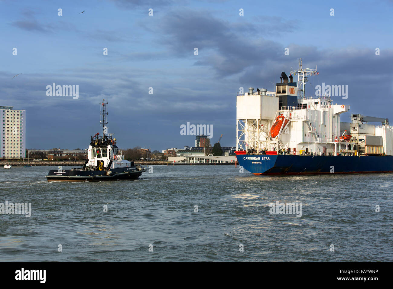 Working tug boat guiding a large container ship through the narrow ...