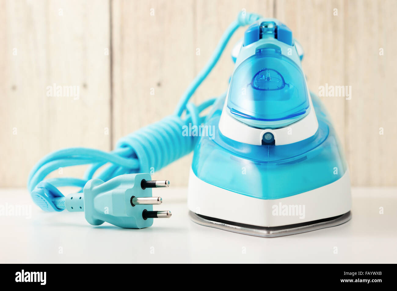 Steam iron on white table with wood wall background Stock Photo - Alamy