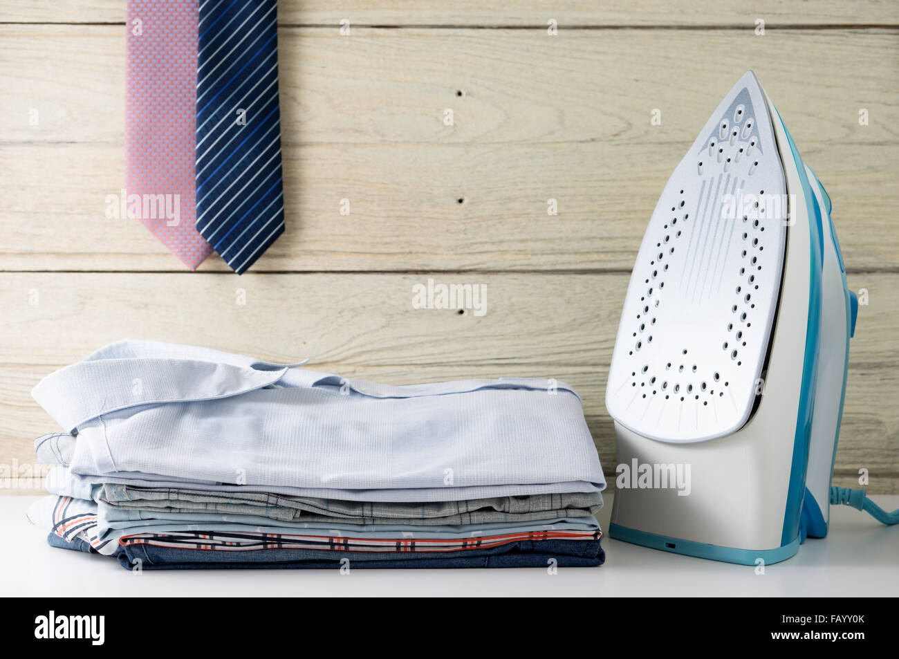Ironing clothes laundry housework with stack of shirts and tie hanging ...