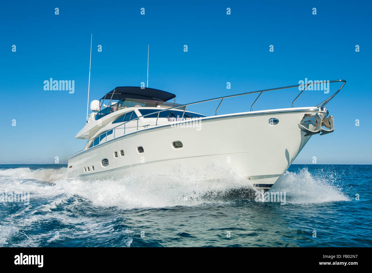 A luxury private motor yacht under way on tropical sea with bow wave ...