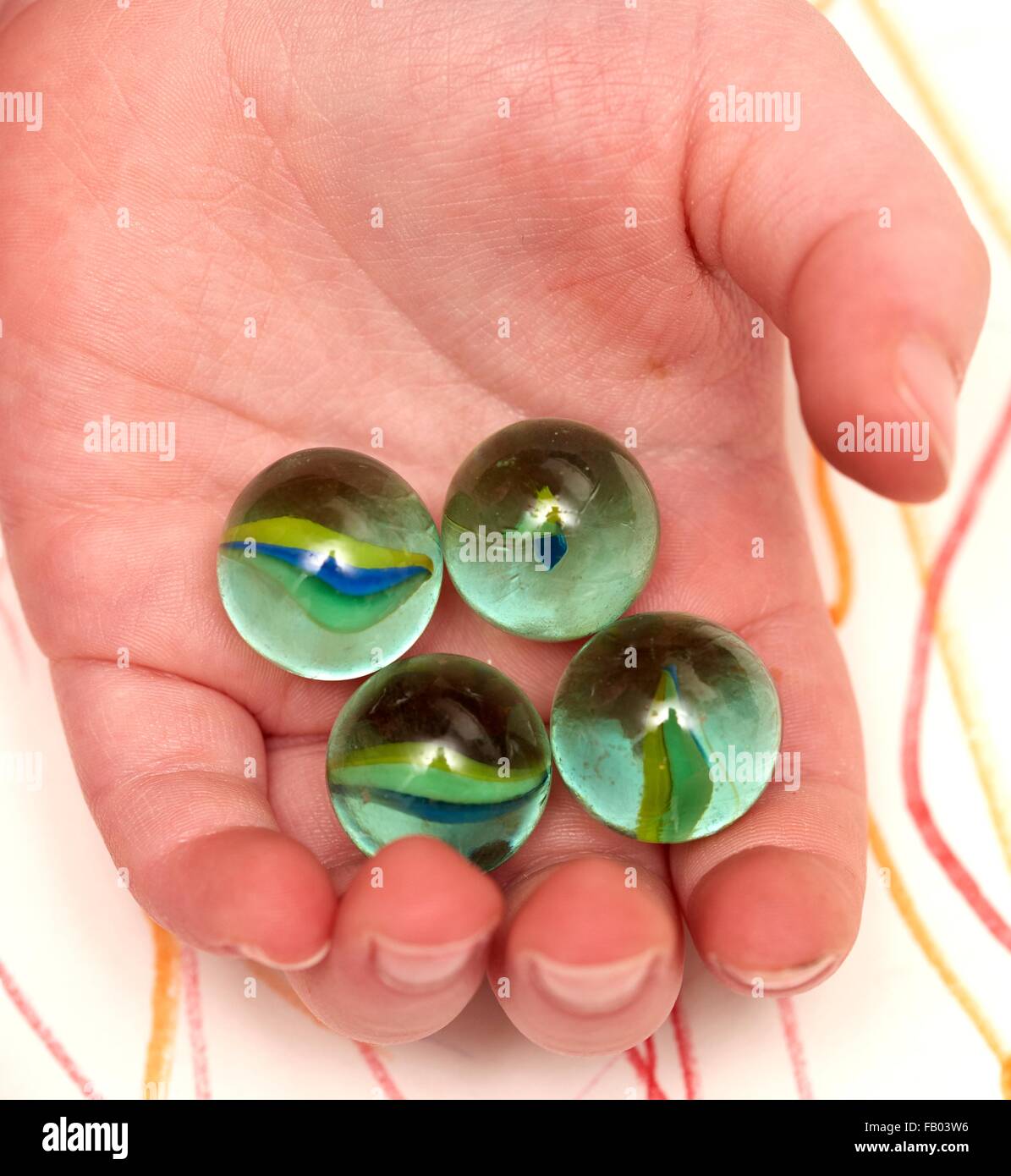 4 marbles being held in the hand Stock Photo - Alamy