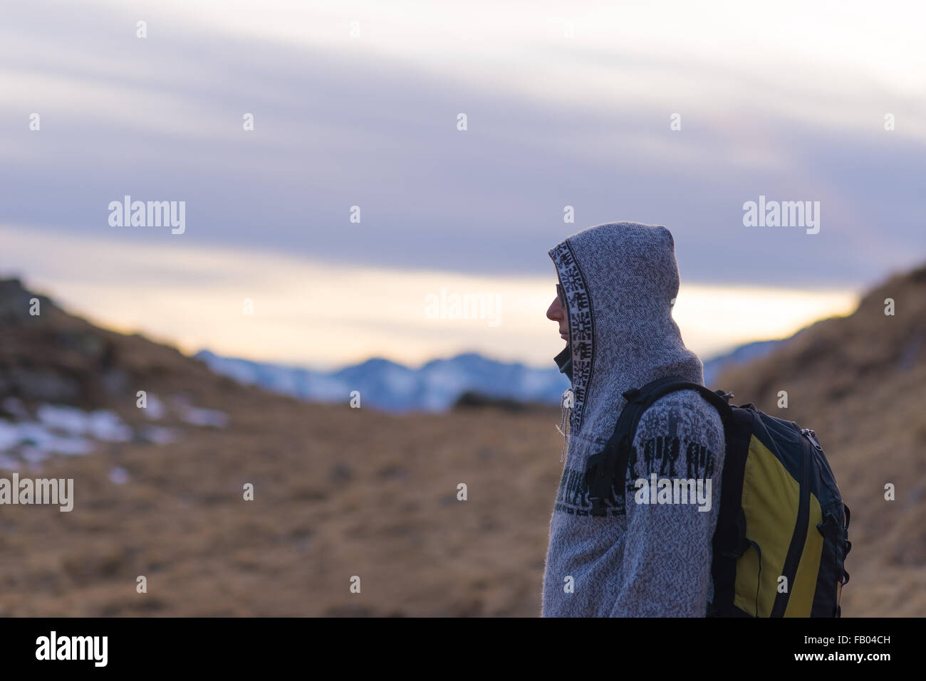 Female hiker with backpack, jacket and hood resting in the cold on the ...