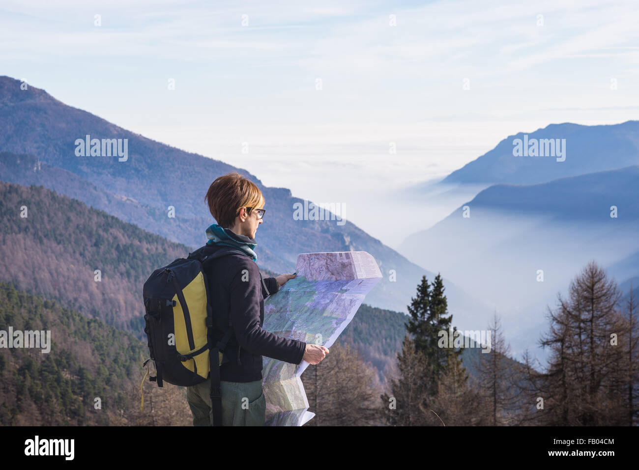 Female hiker with backpack reading trekking map while resting at ...