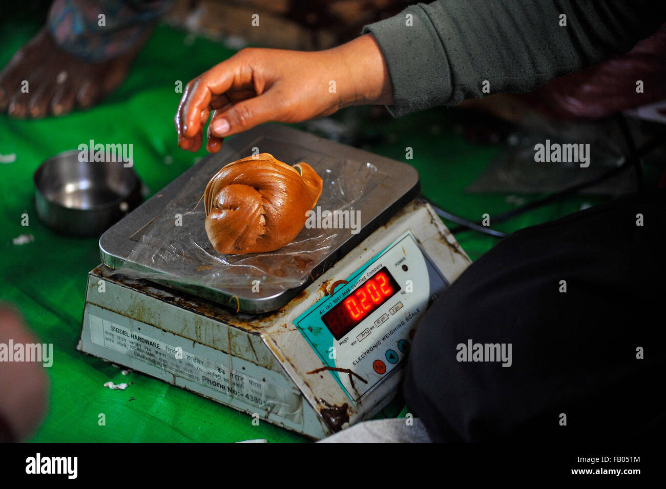 A local weighs the molten raw hardened molasses or “Chaku” for the ...