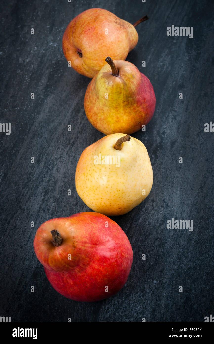 Four bright ripe bartlett pears on dark grey background from above ...