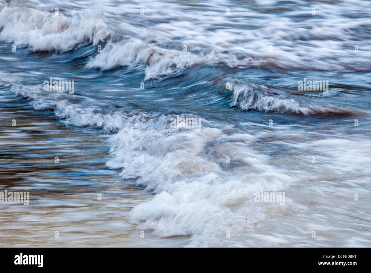 Blue foamy ocean waves breaking in shallow water, in-camera motion blur ...