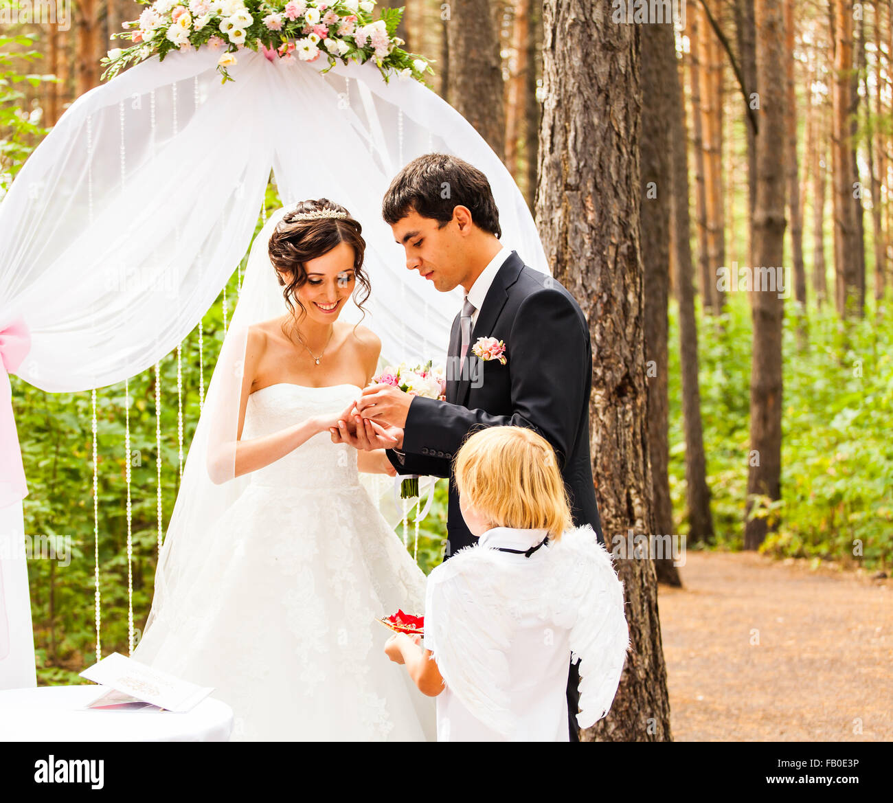 Groom slipping ring on finger of bride at wedding Stock Photo - Alamy