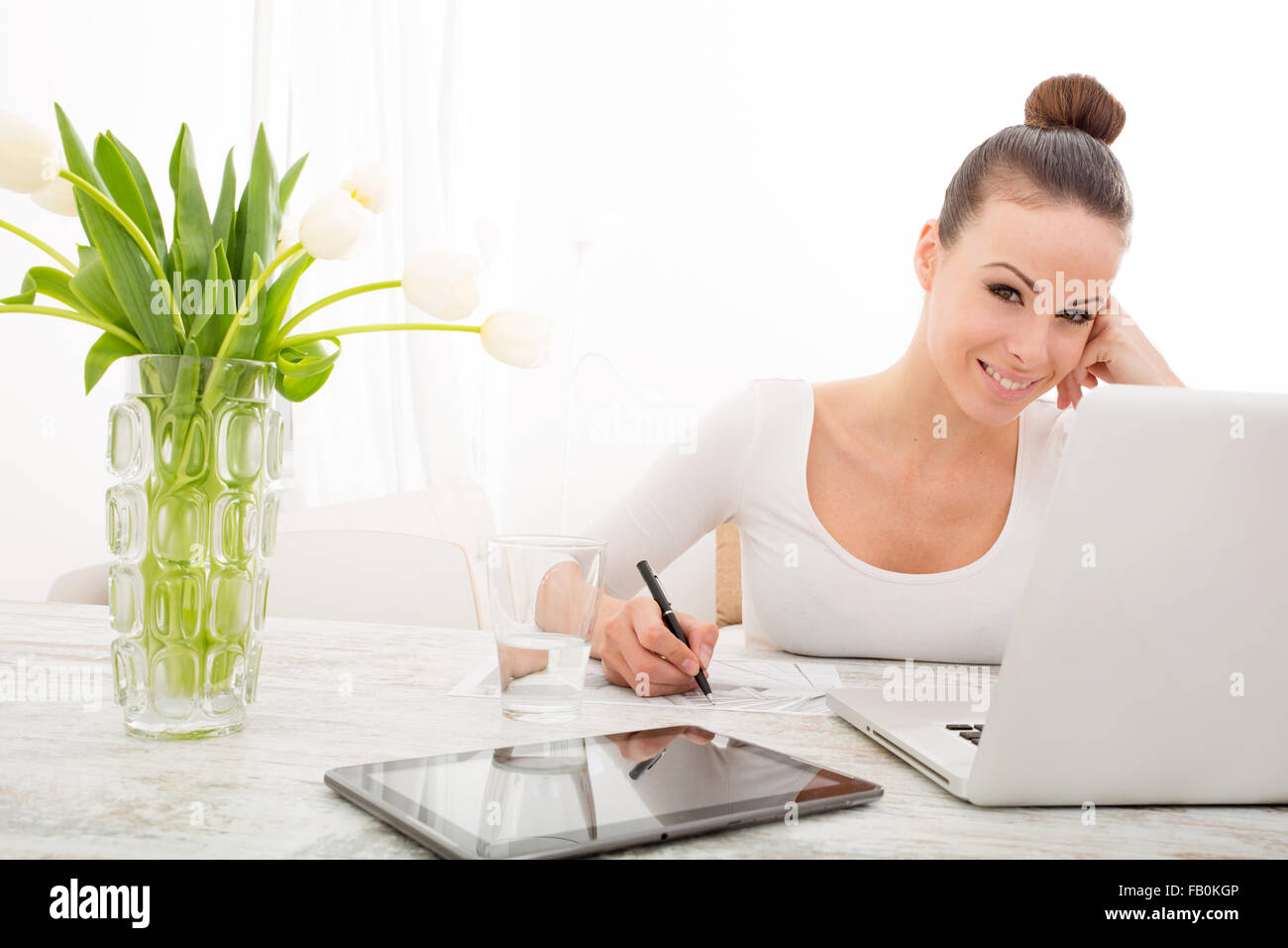 A young adult woman drawing an architectural plan at home with laptop ...