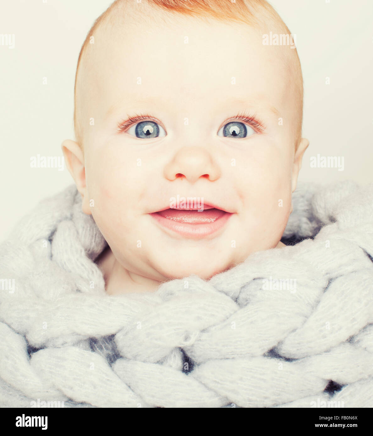 little cute red head baby in scarf all over him close up isolated ...
