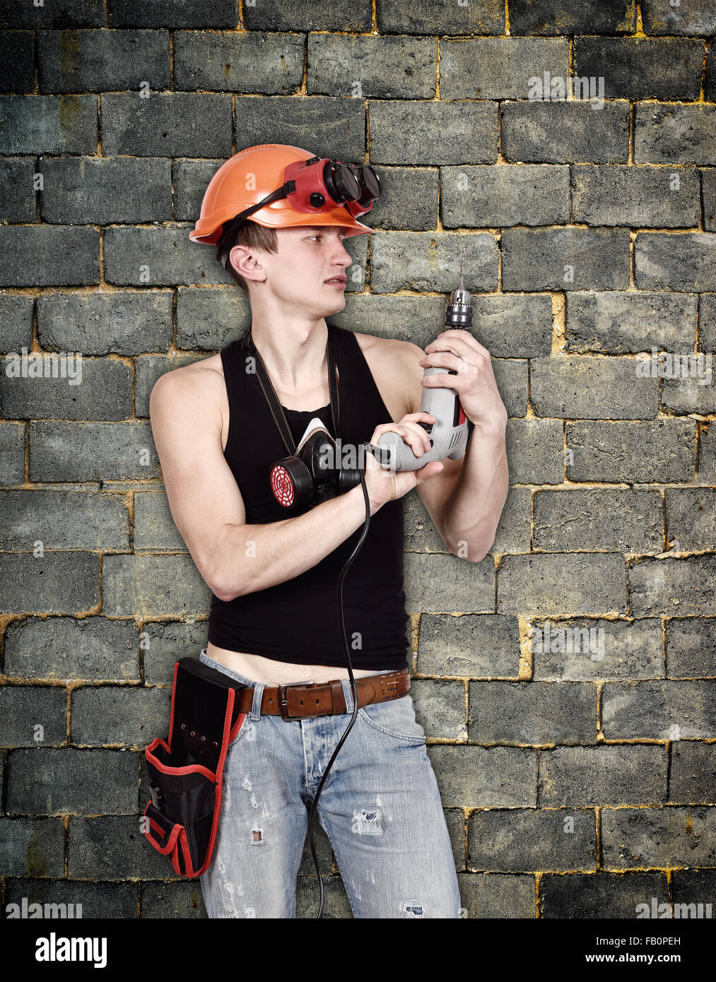 worker with drill on a brick wall background Stock Photo - Alamy