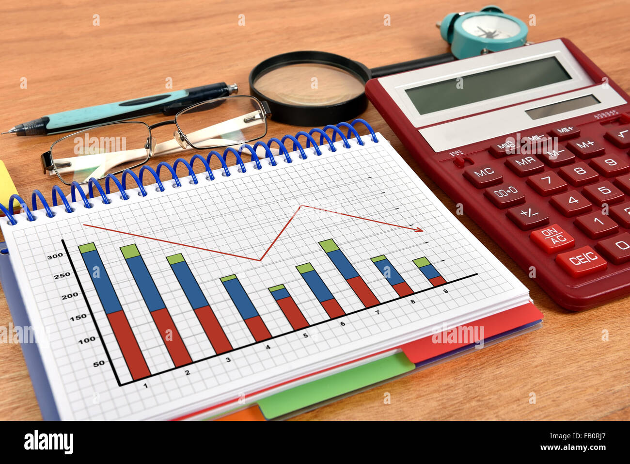 falling chart in notebook and red calculator Stock Photo - Alamy