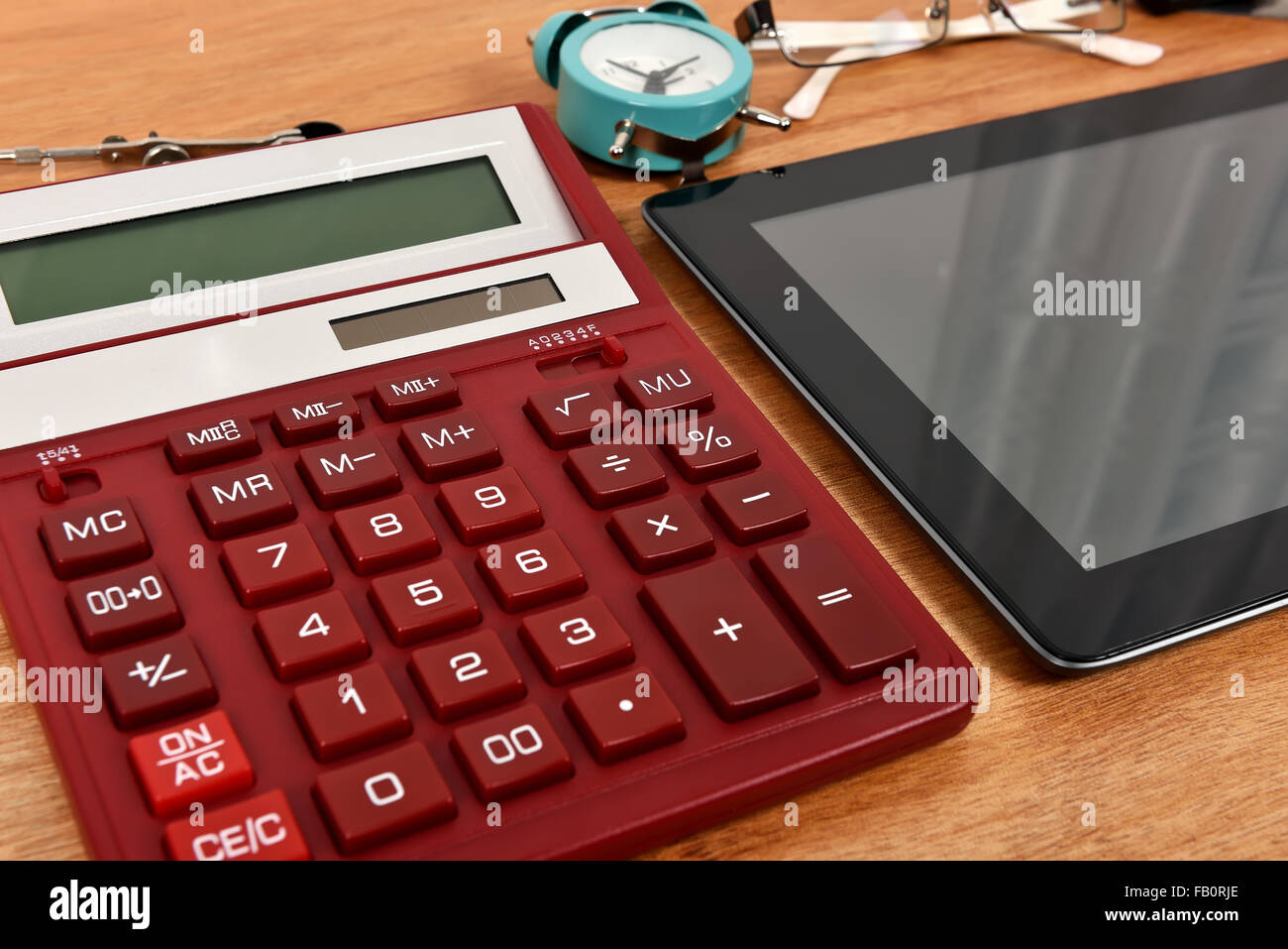 red calculator and tablet pc with empty screen on table Stock Photo - Alamy