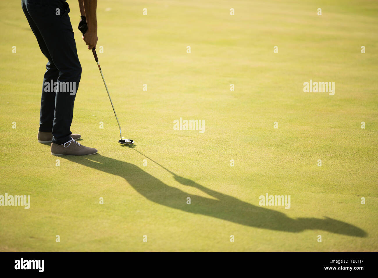 Golf ball, putter and boy's legs on green Stock Photo - Alamy