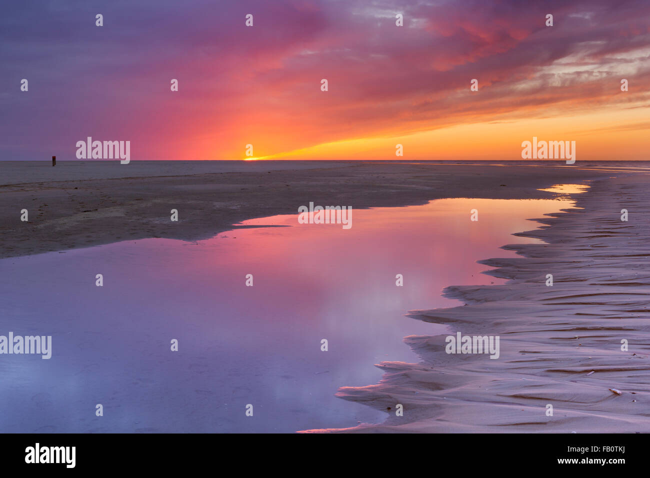 Sunset colours reflected in a tidal pool on a beach on the island of ...