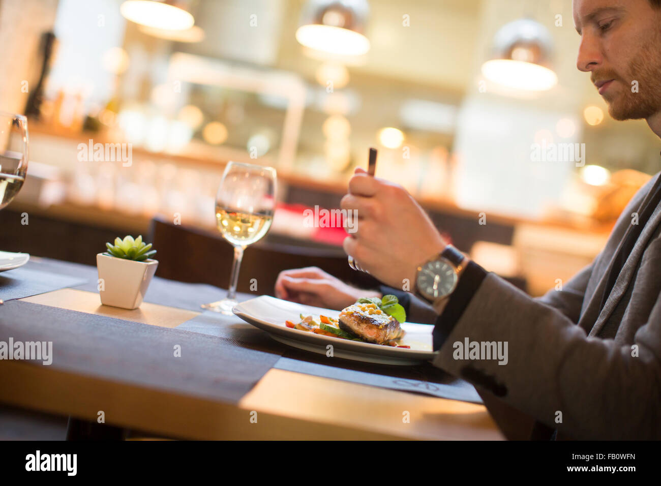 Young man eating grilled salmon with sauce and herbs served at ...
